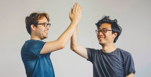 Two men high-fiving, one white with brown hair, the other Asian with ...